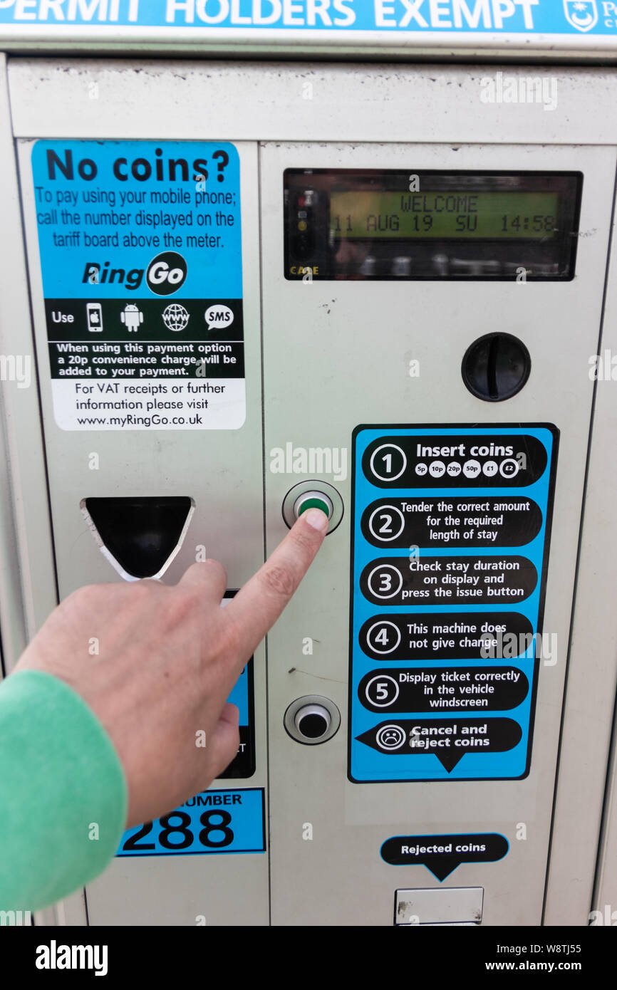A Button being pressed on a parking ticket meter to collect a ticket ...