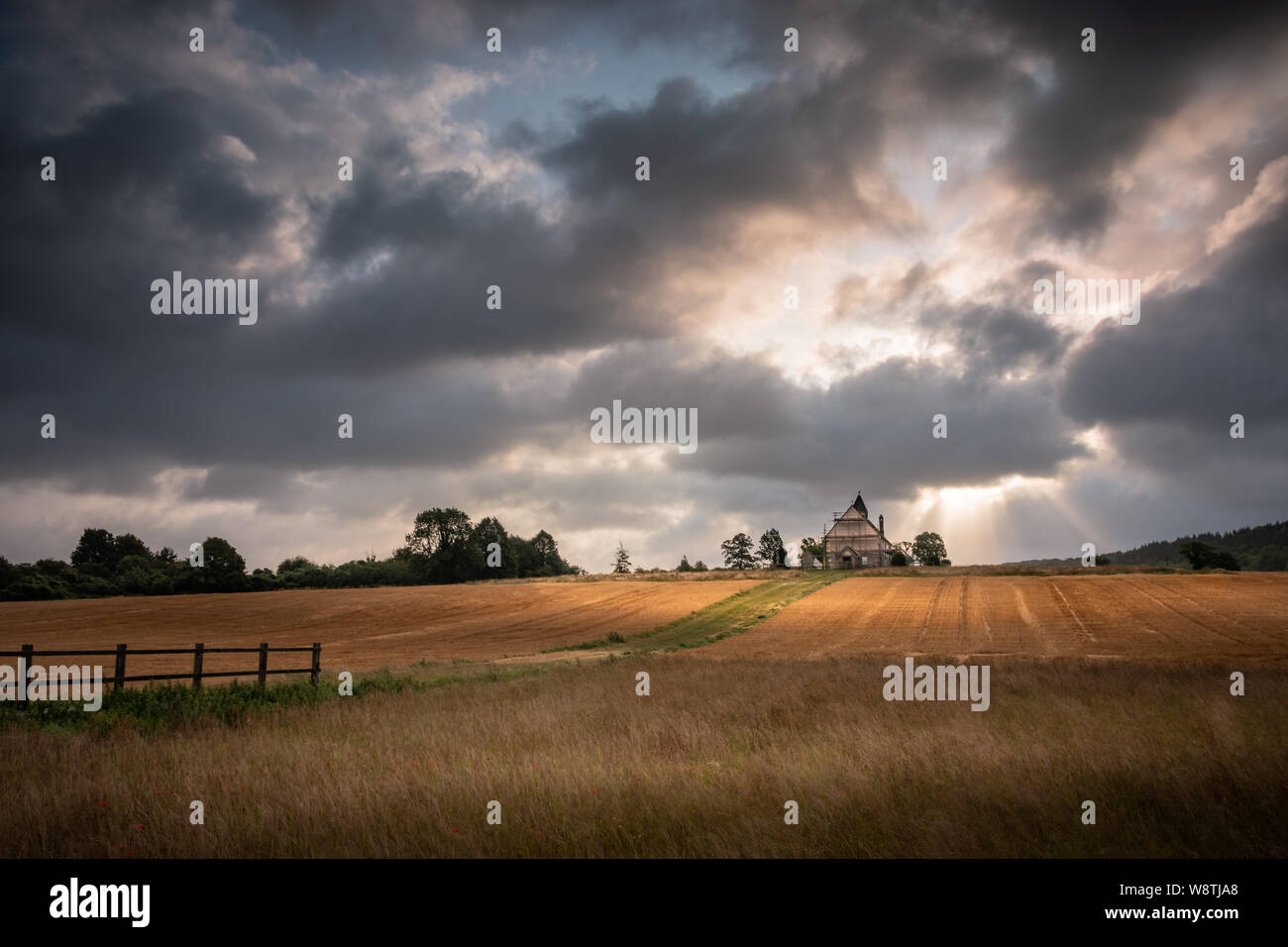 An old church on a on a hill with light rays coming through the clouds ...