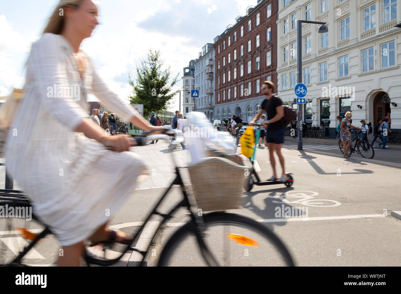 Copenhagen bike - a woman riding a bicycle and a man on a scooter in ...