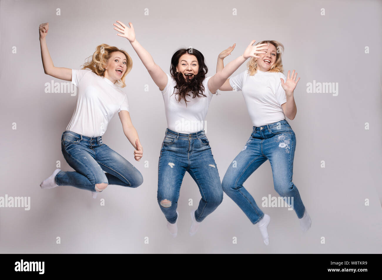 Three friends in casual clothes dancing and jumping. Different, but ...