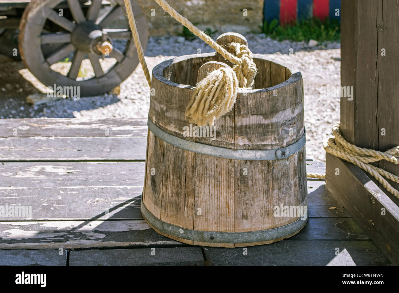 Wooden bucket with a rope stands on the lid of a well in the courtyard ...