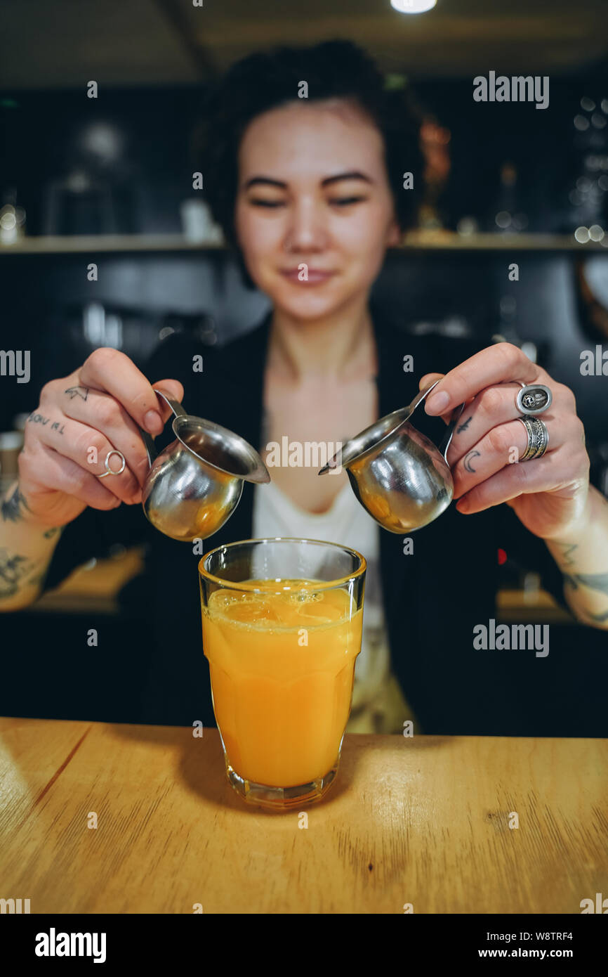 KIEV, UKRAINE - APRIL 14, 2019 A girl makes a orange coffee cocktail ...