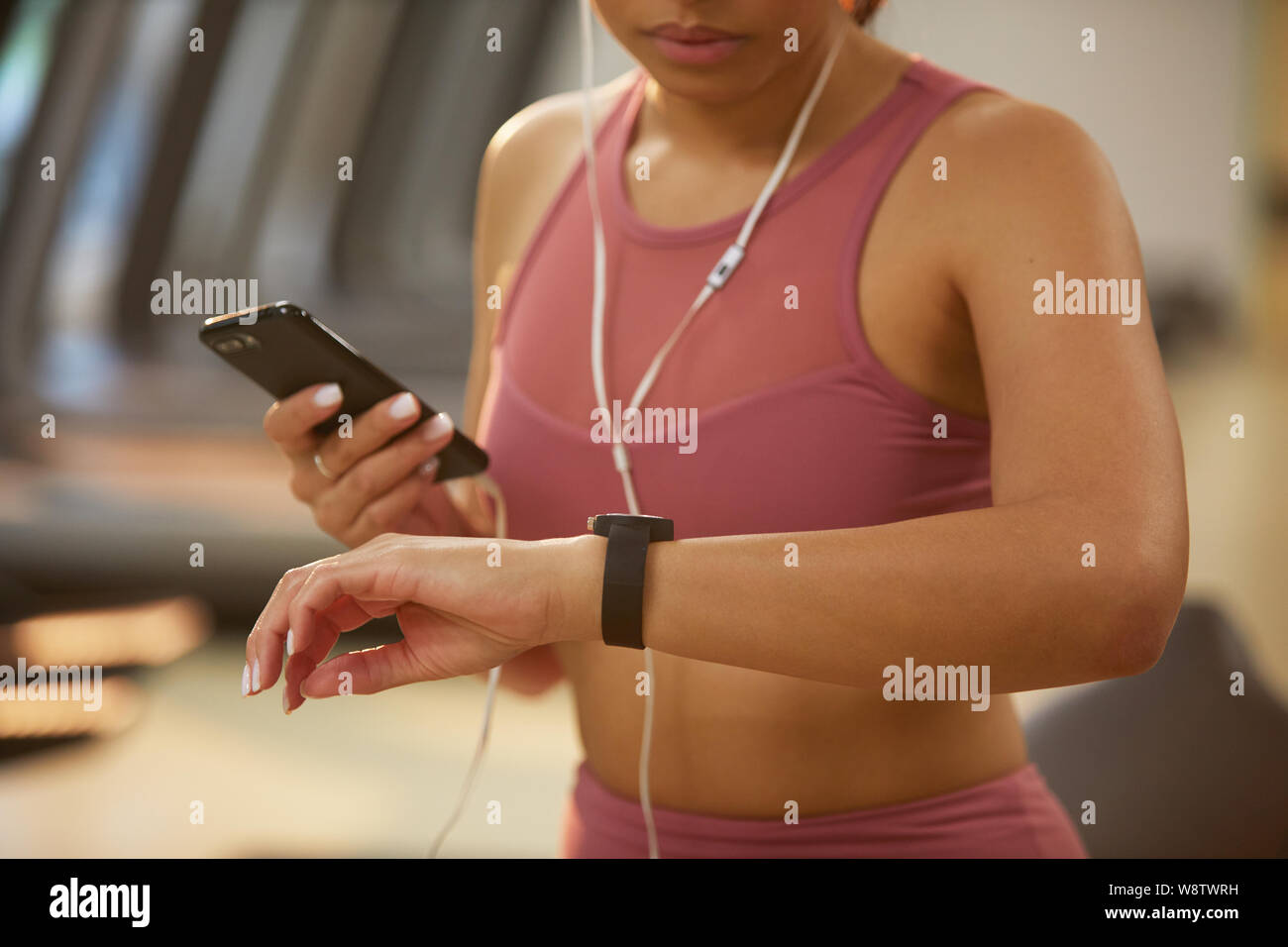 Mid section portrait of young woman checking smartwatch during workout ...
