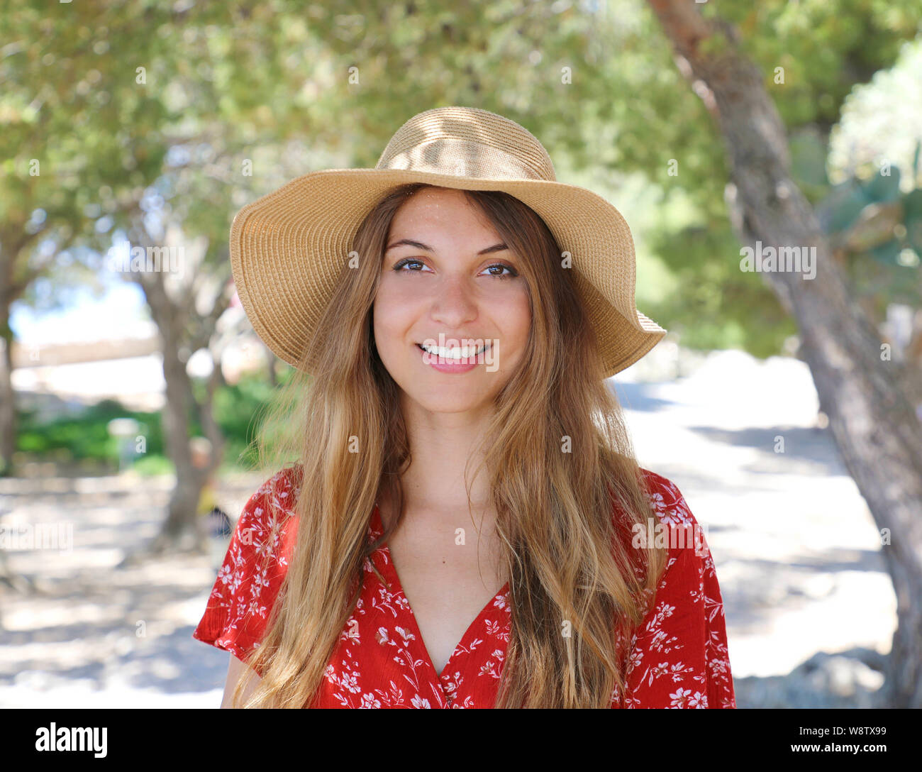 Portrait of a beautiful smiling girl wearing red dress and hat looking ...