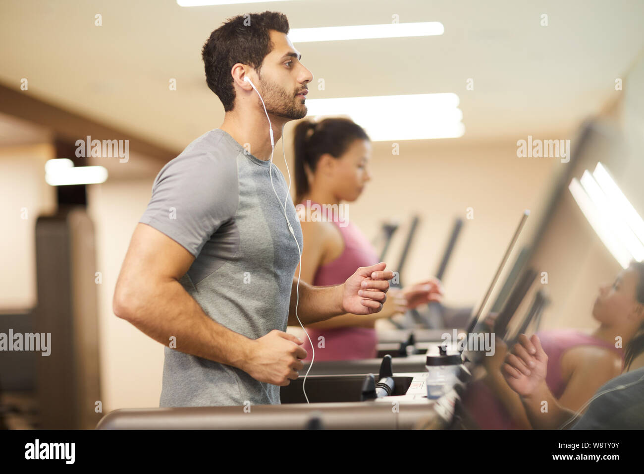 Side view portrait of handsome Middle-Eastern man running on treadmill ...