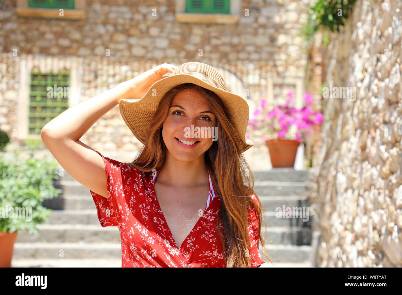Beautiful tourist girl with hat and red dress posing on cozy italian ...