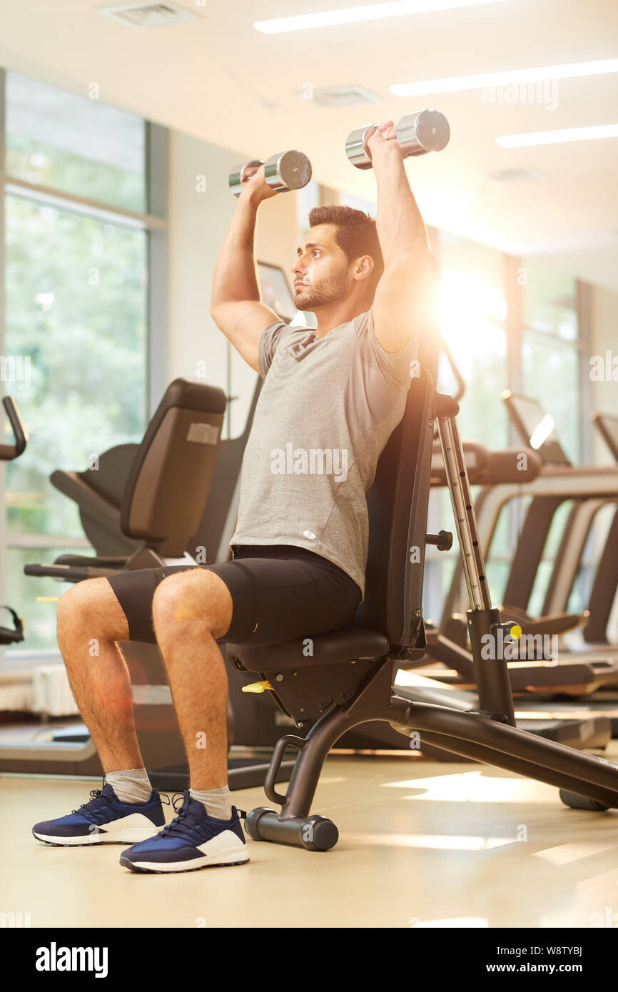 Full length portrait of handsome muscular man working out in gym using ...