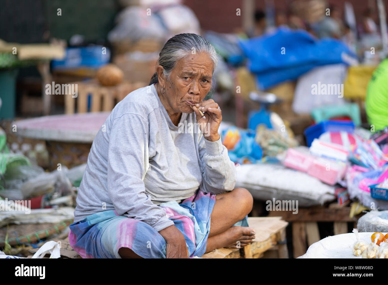 Environmental portrait of a woman smoking a cigarette,within a market ...