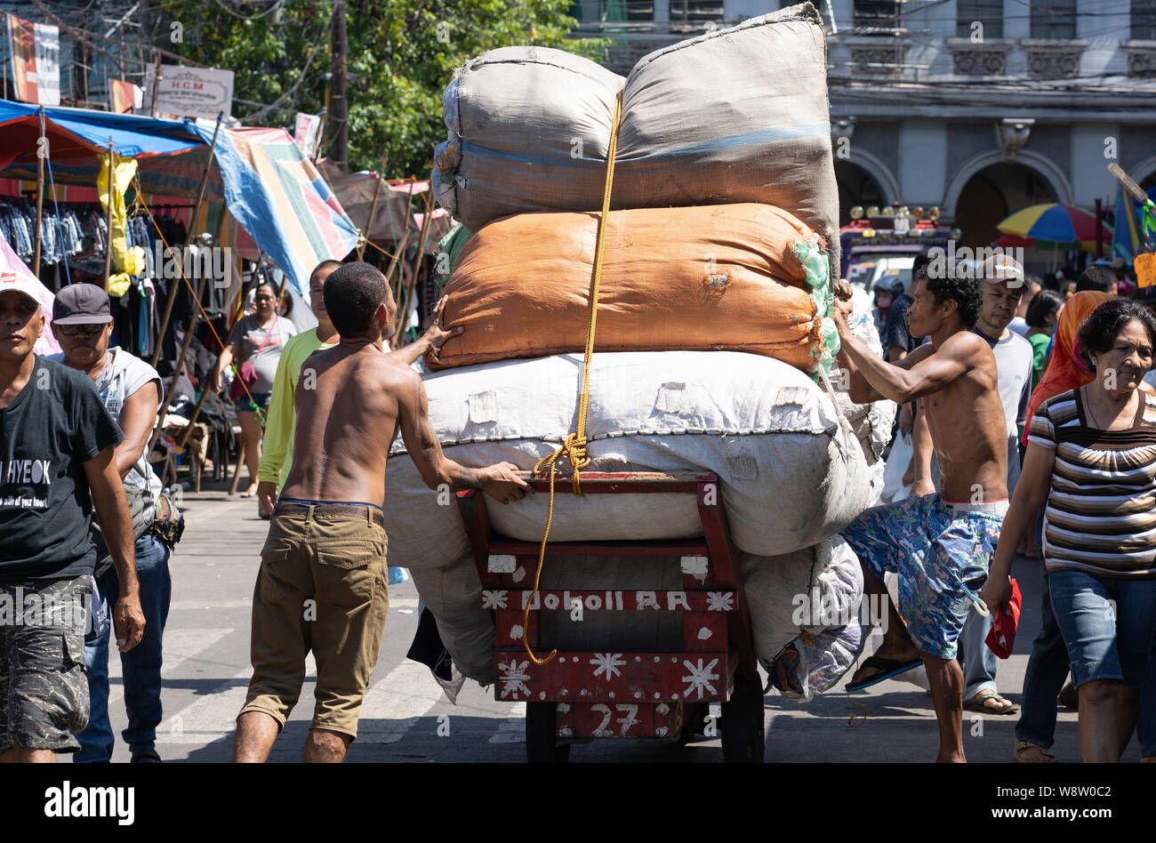 Two men moving a loaded push cart within a market area,Cebu City ...
