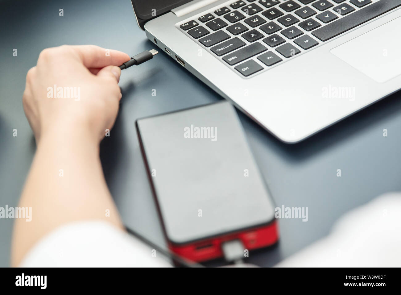 Woman charges her laptop with power bank using USB-C cable Stock Photo ...