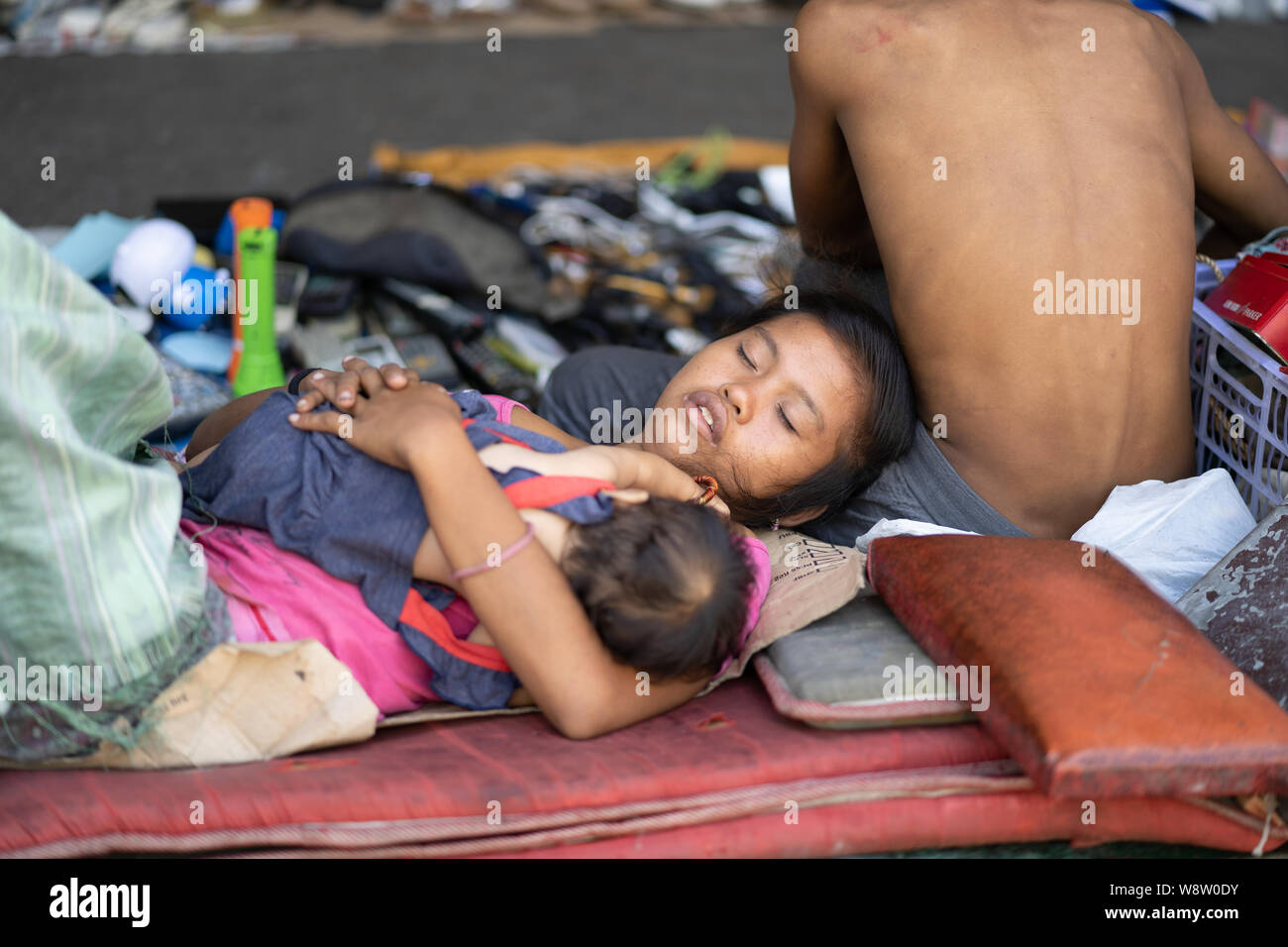 A young Filipino girl holding a child whilst asleep within a downtown ...