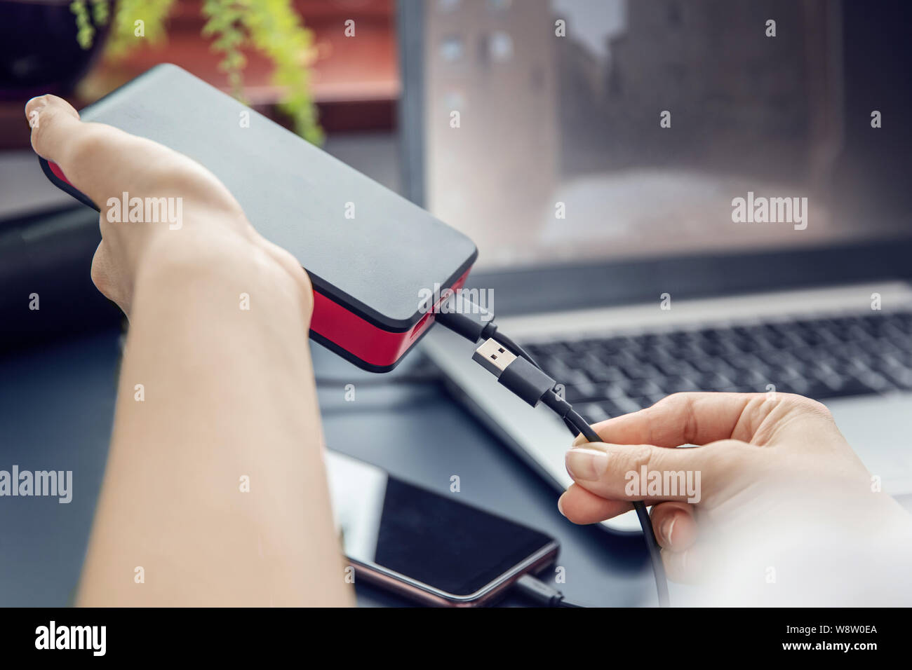 Womans's hands connect another device to power bank Stock Photo - Alamy