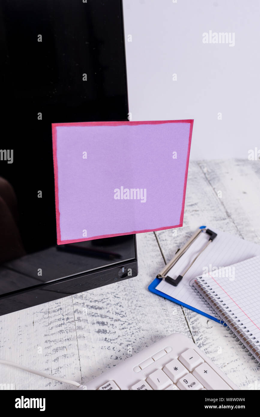 Note paper taped to black computer screen near keyboard and stationary ...