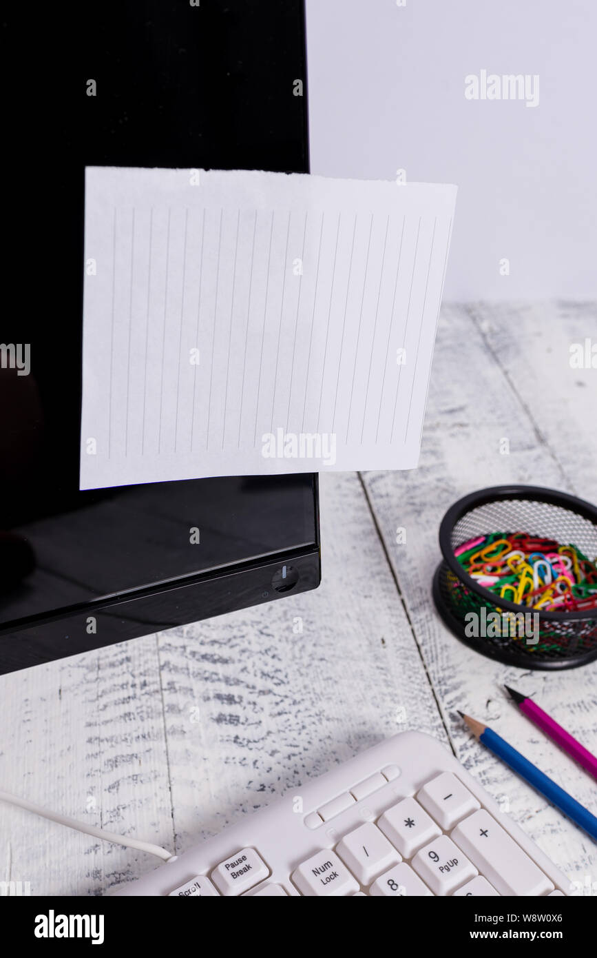 Note paper taped to black computer screen near keyboard and stationary ...