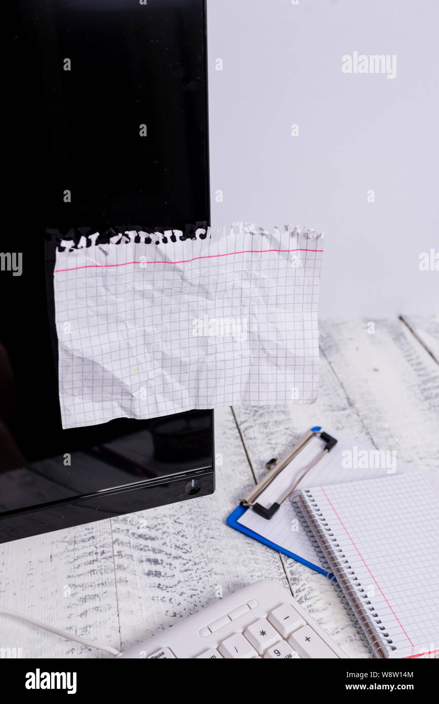 Note paper taped to black computer screen near keyboard and stationary ...