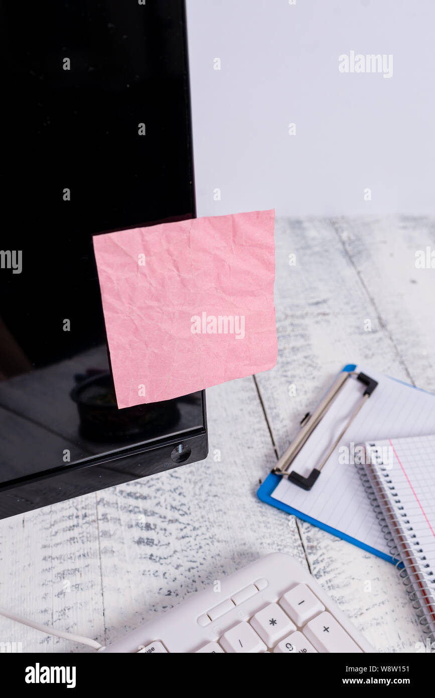 Note paper taped to black computer screen near keyboard and stationary ...