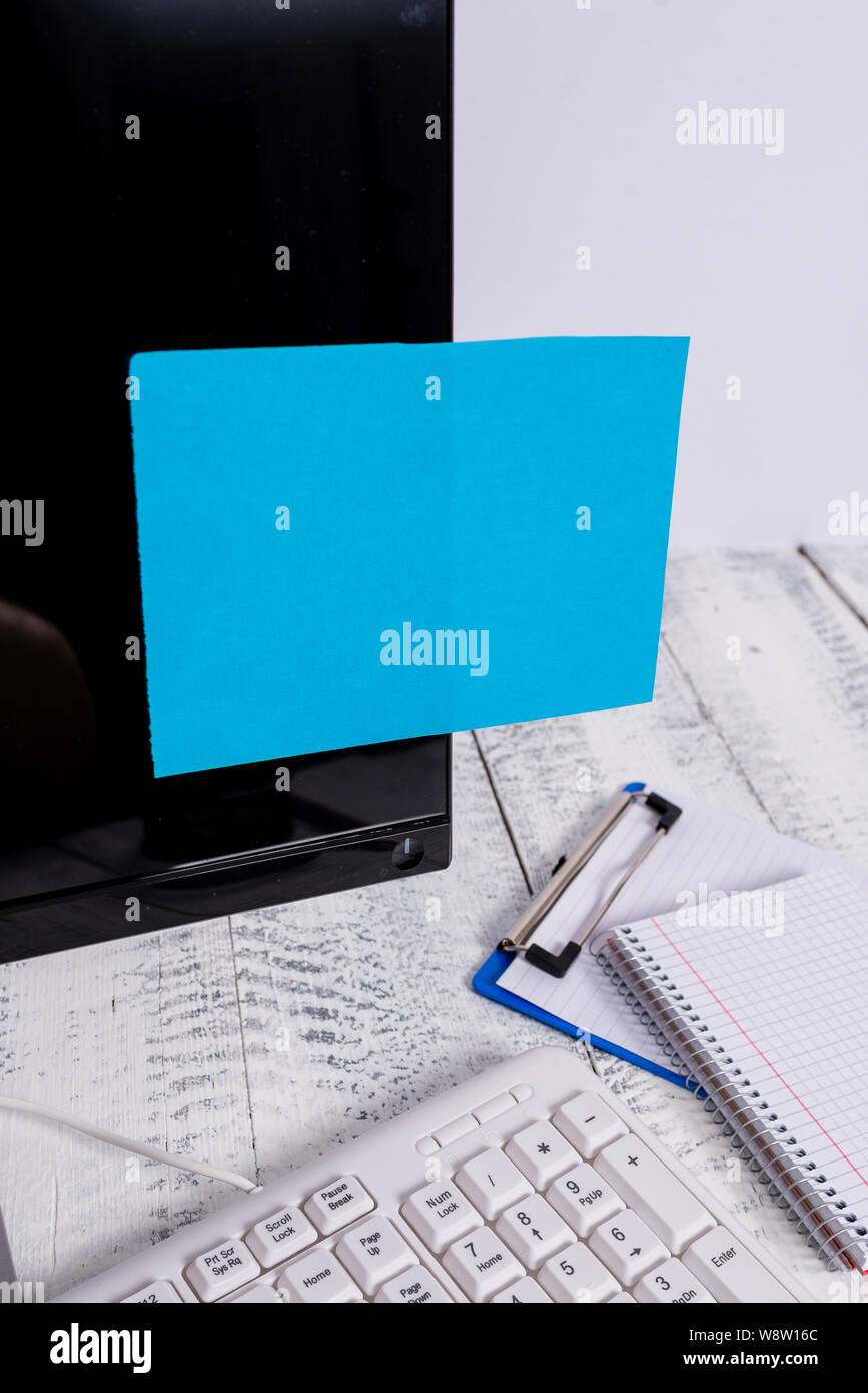 Note paper taped to black computer screen near keyboard and stationary ...