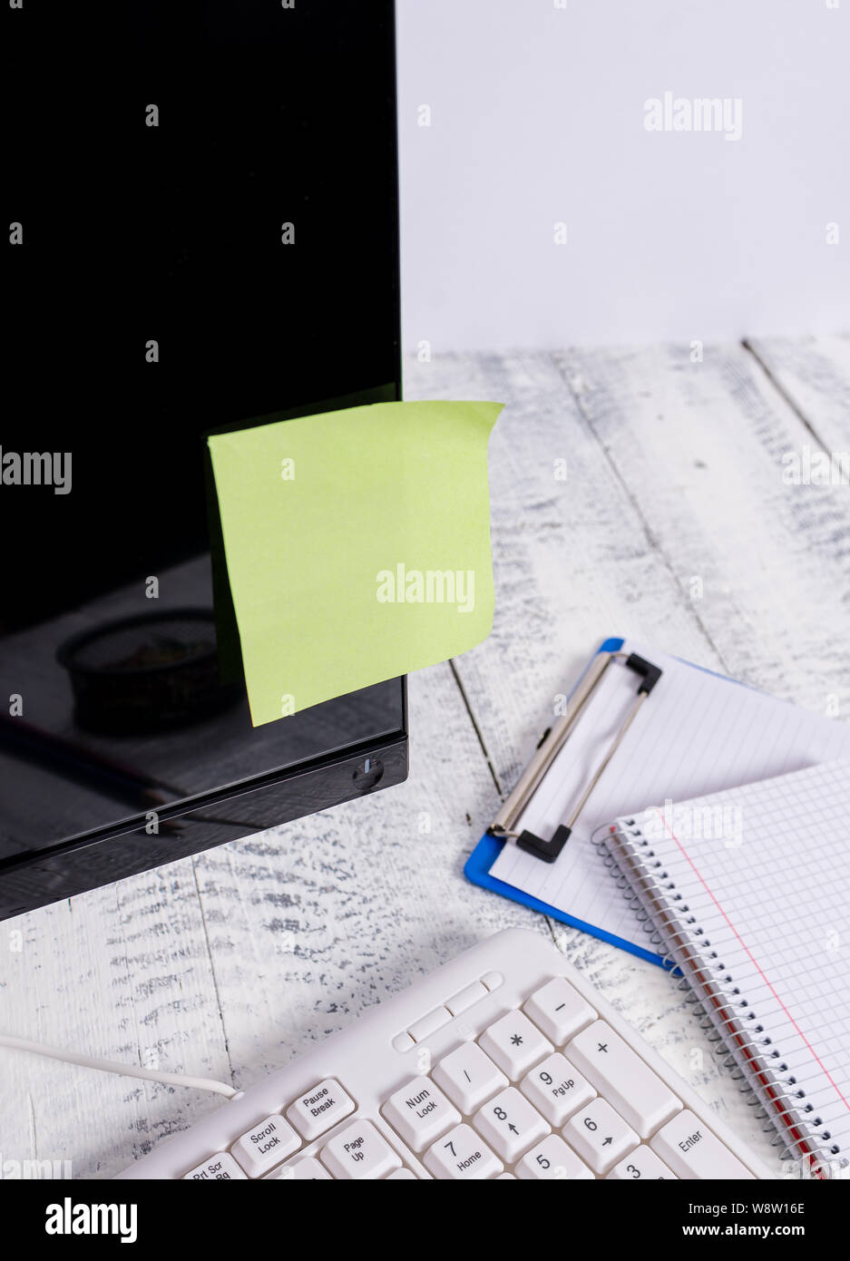 Note paper taped to black computer screen near keyboard and stationary ...