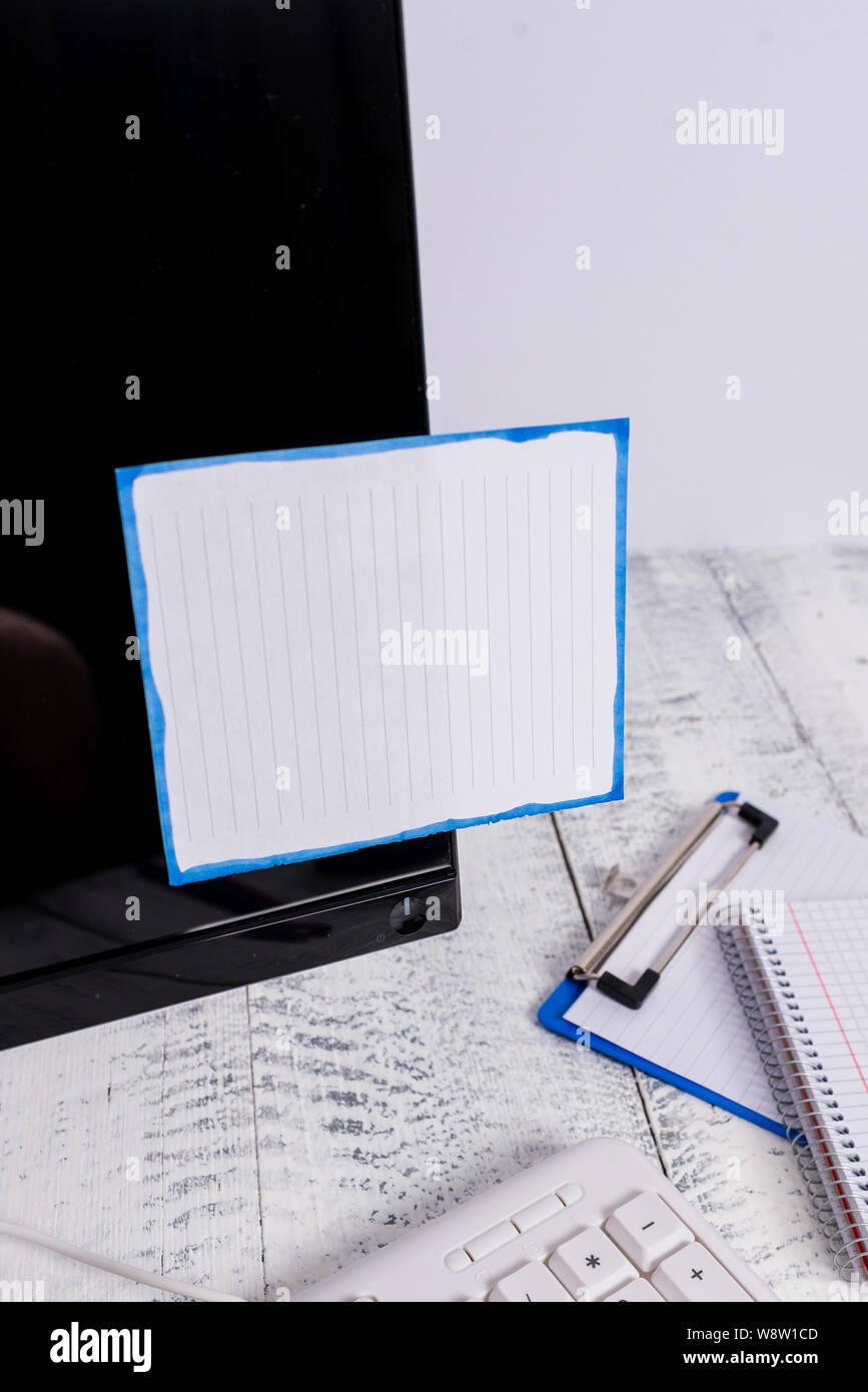 Note paper taped to black computer screen near keyboard and stationary ...