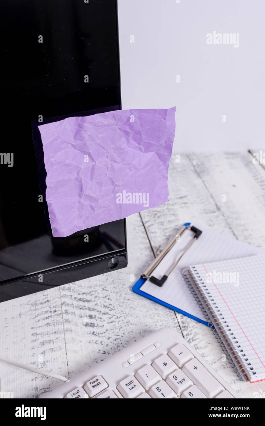 Note paper taped to black computer screen near keyboard and stationary ...