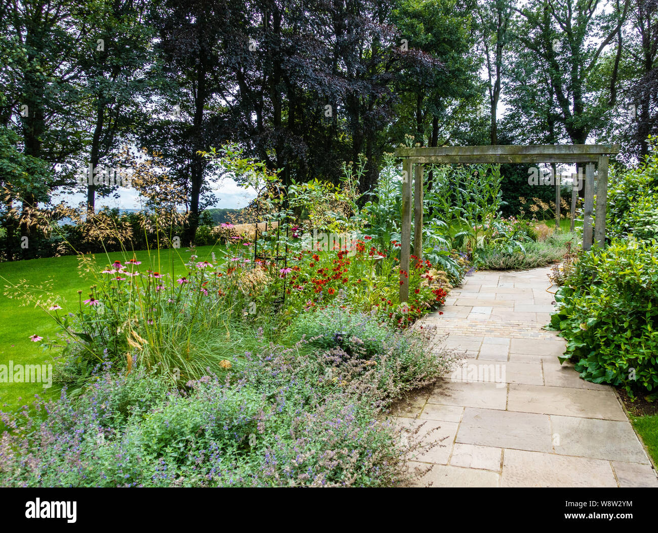 Stone path through arch into English country garden Stock Photo - Alamy