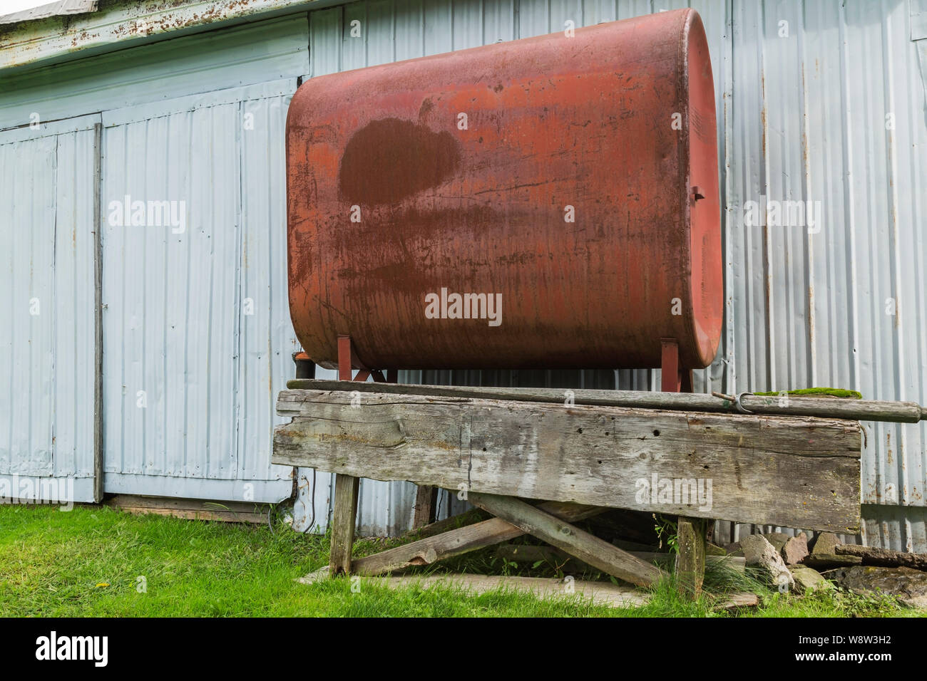 Red painted heating oil tank on old elevated wooden platform next to ...