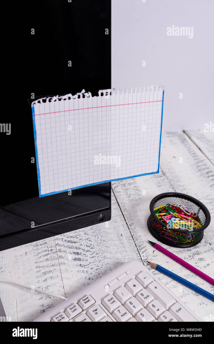 Note paper taped to black computer screen near keyboard and stationary ...