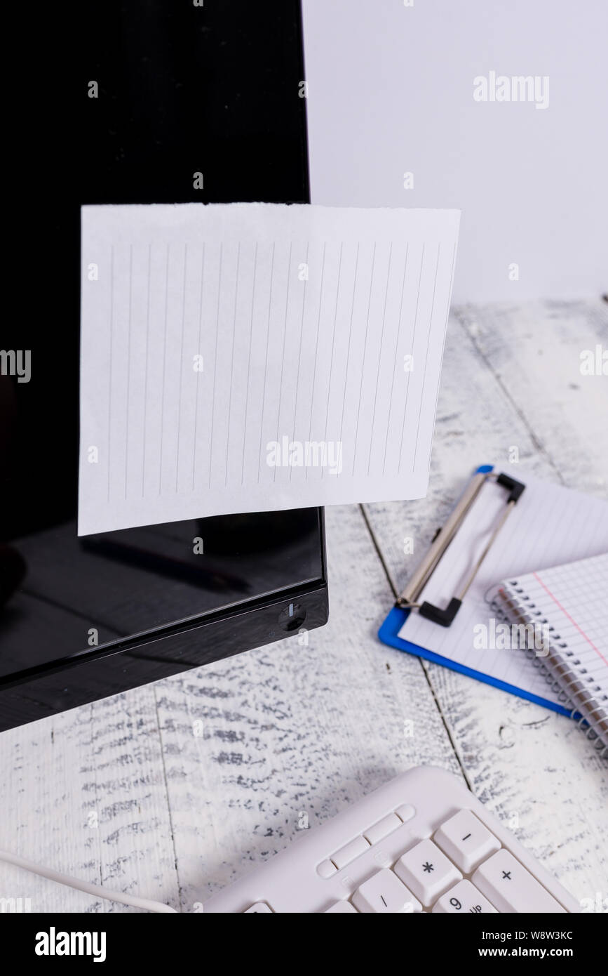 Note paper taped to black computer screen near keyboard and stationary ...