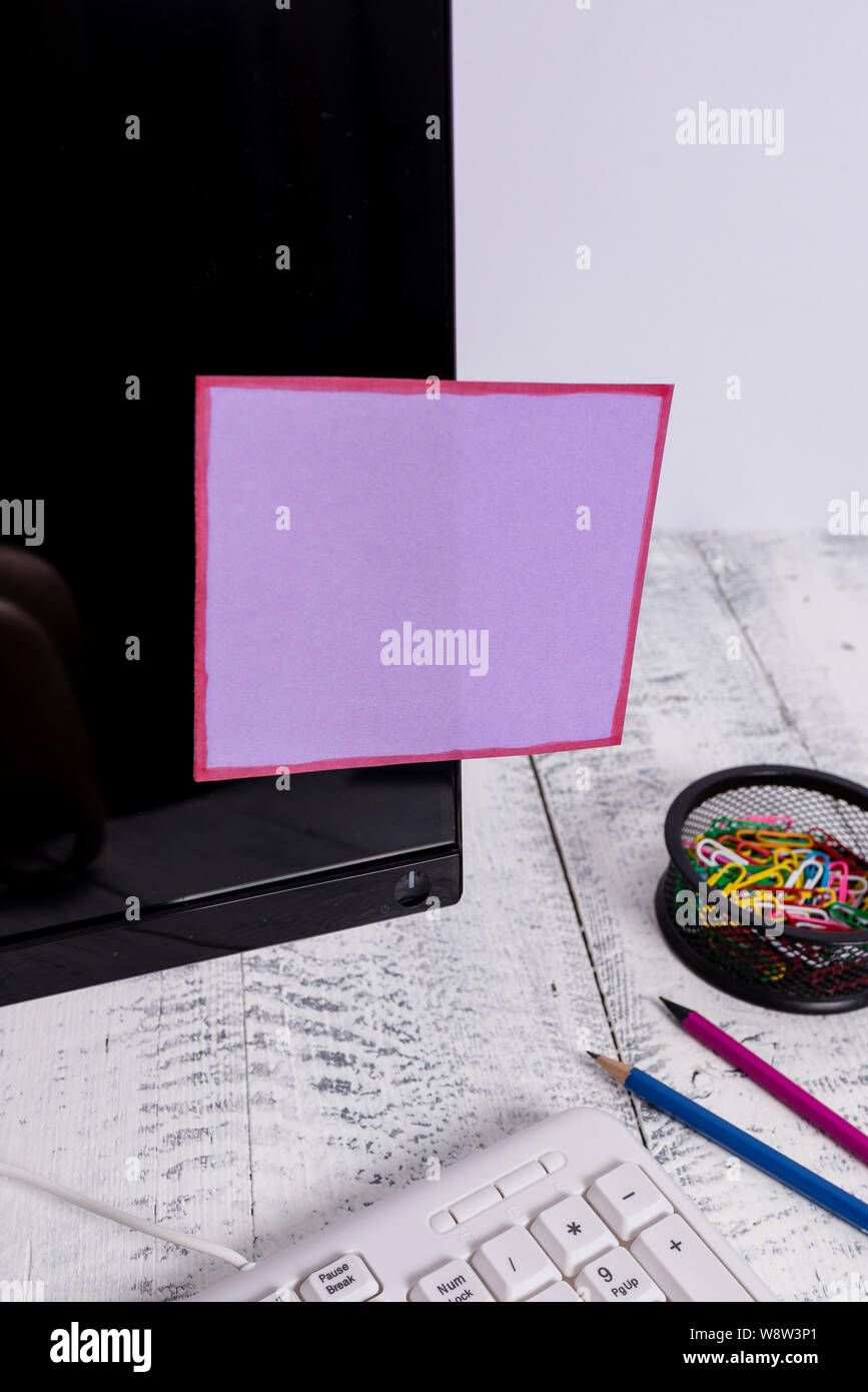 Note paper taped to black computer screen near keyboard and stationary ...