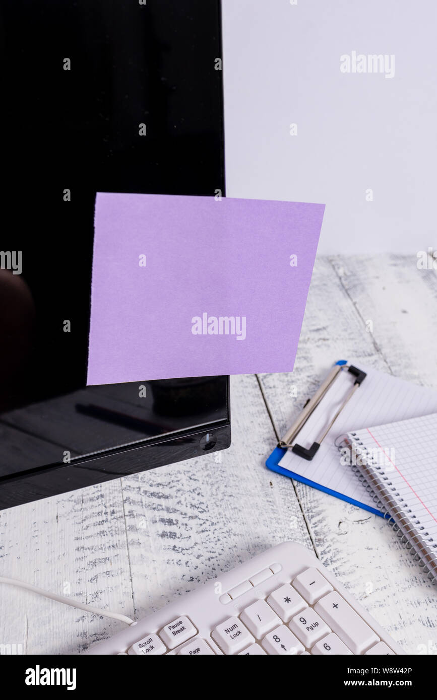 Note paper taped to black computer screen near keyboard and stationary ...