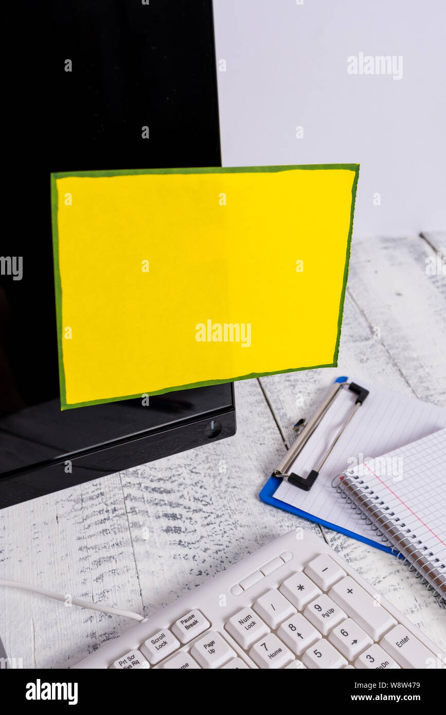 Note paper taped to black computer screen near keyboard and stationary ...