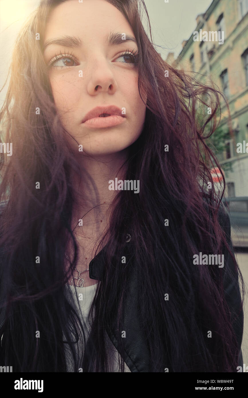 Pensive Good Looking Girl Posing With Windy Hair Ouside Sunflares Of Wide Anglw Smartphone Lens