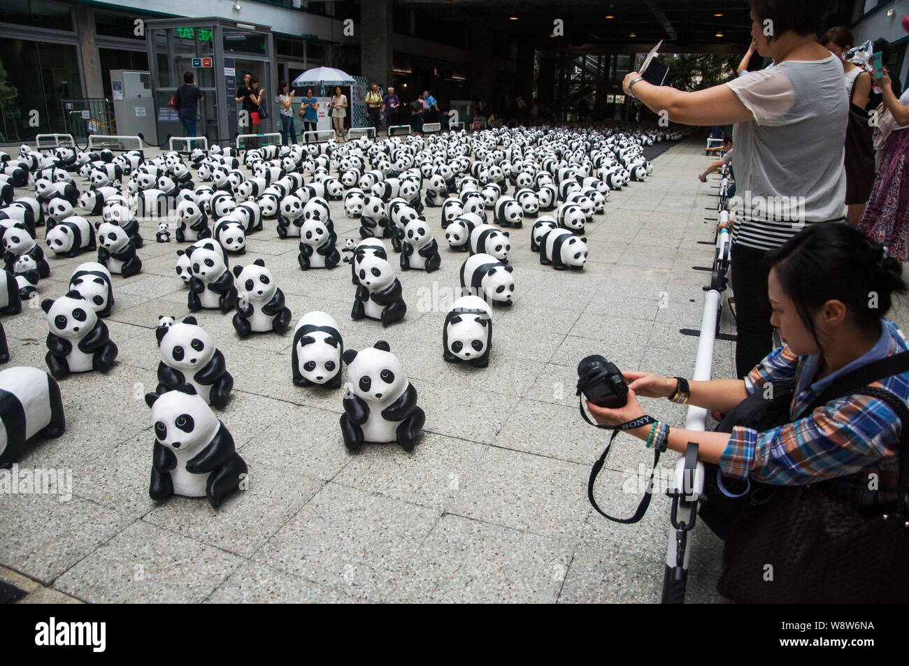 Visitors take photos of the paper pandas created by French artist Paulo ...