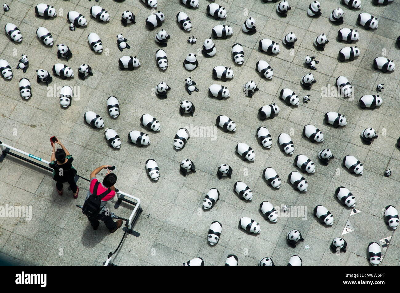 Visitors take photos of the paper pandas created by French artist Paulo ...