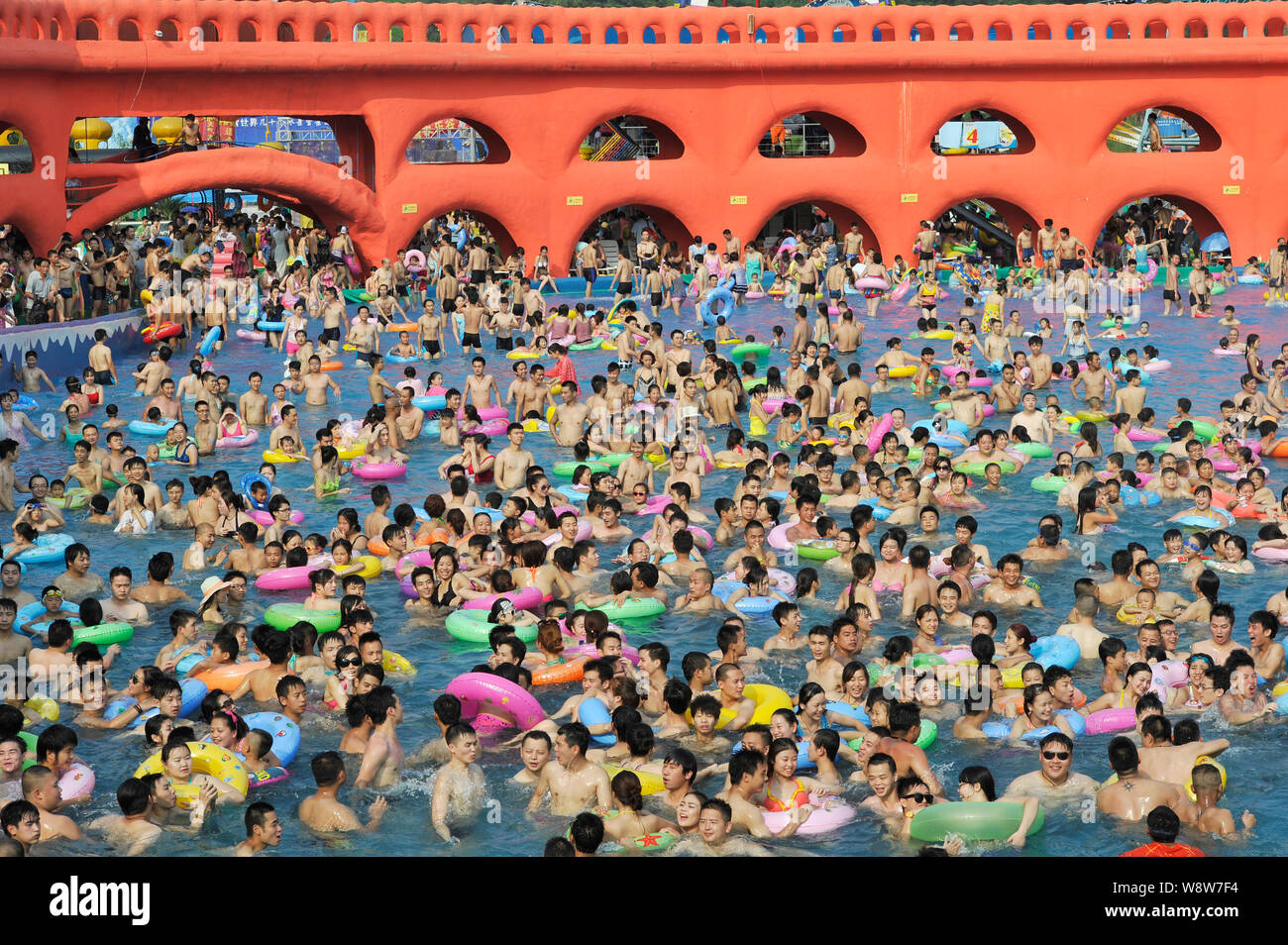 Holidaymakers crowd a swimming pool to cool down at a water park on a ...