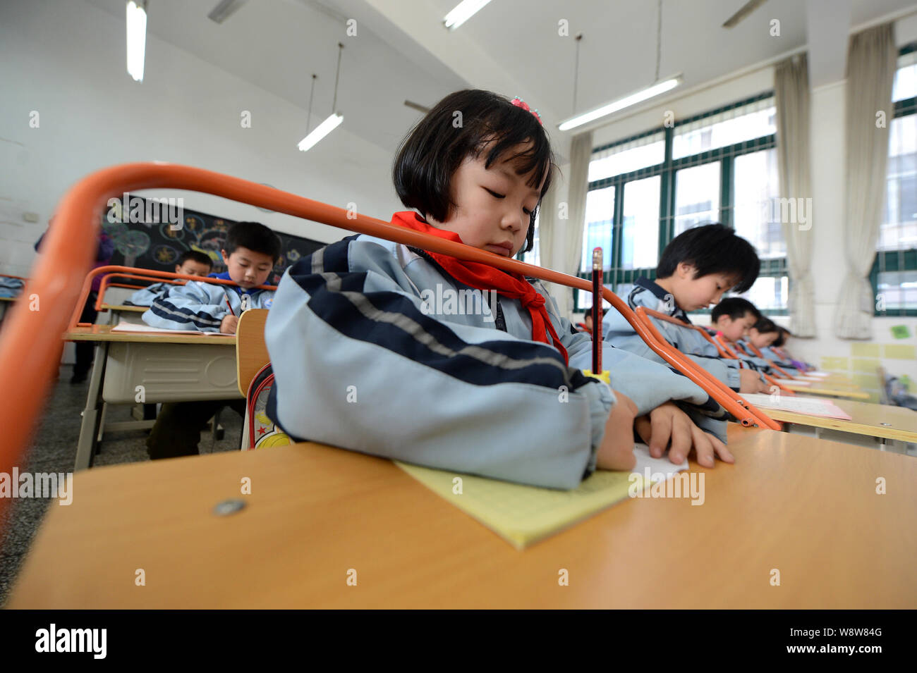 A Chinese schoolgirl writes her homework on a desk with a bar installed ...