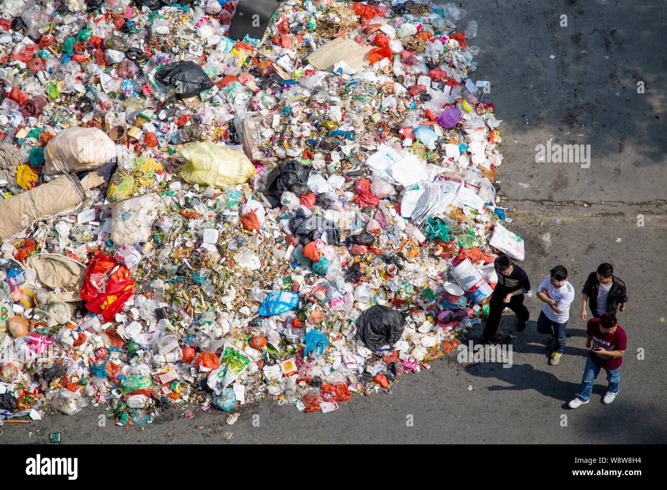 Chinese pedestrians walk past piles of garbage left on a road in Shiyan ...