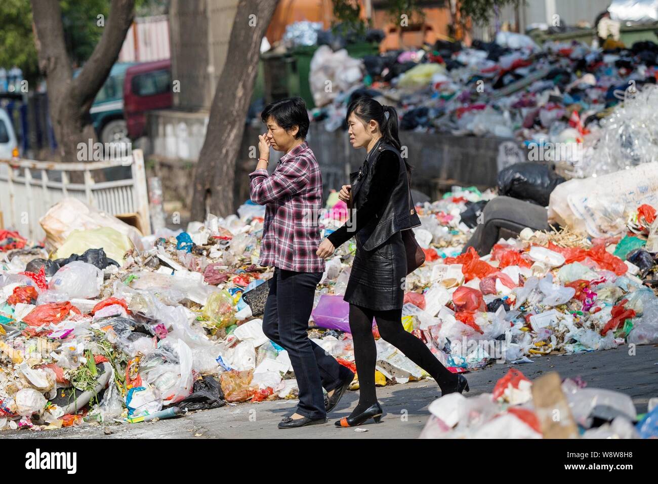 Chinese pedestrians walk past piles of garbage left on a road in Shiyan ...