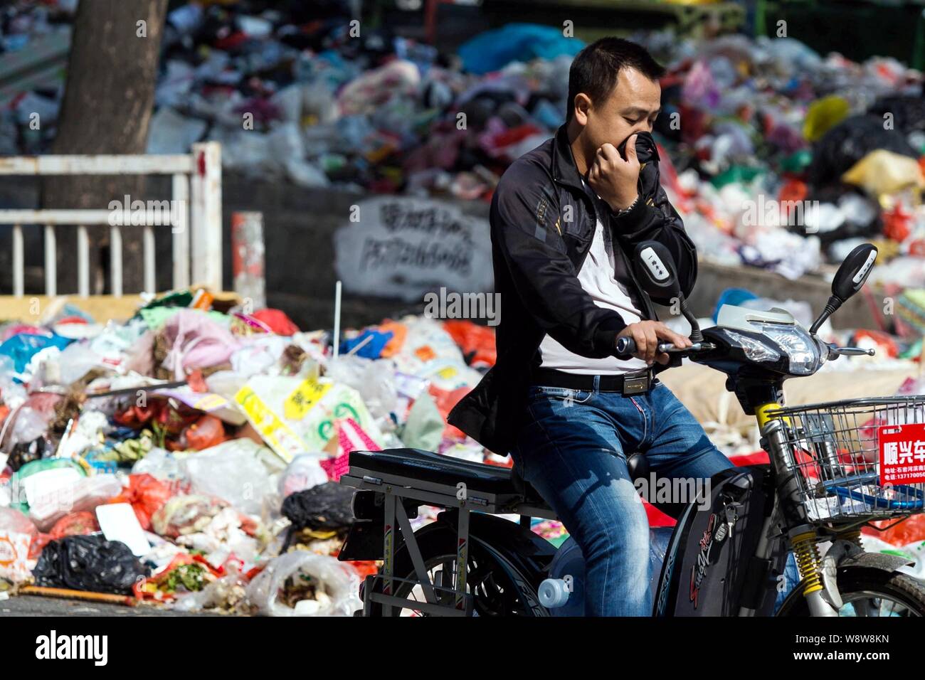 A Chinese cyclist covers his nose with his clothes as he rides past ...