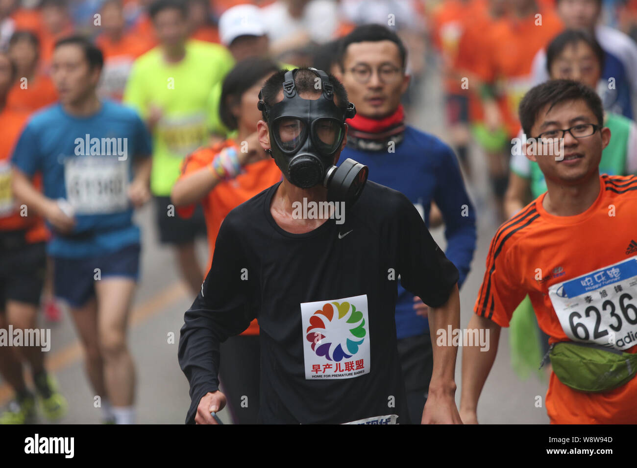 A Chinese participant wearing a gas mask runs with other participants ...