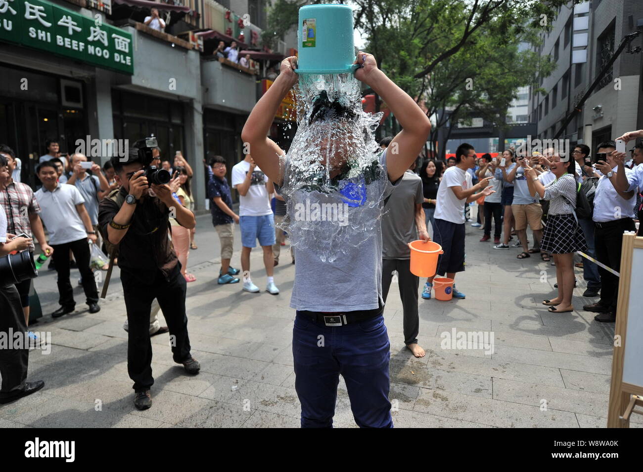 Young people line up along a street to brave the Ice Bucket Challenge ...