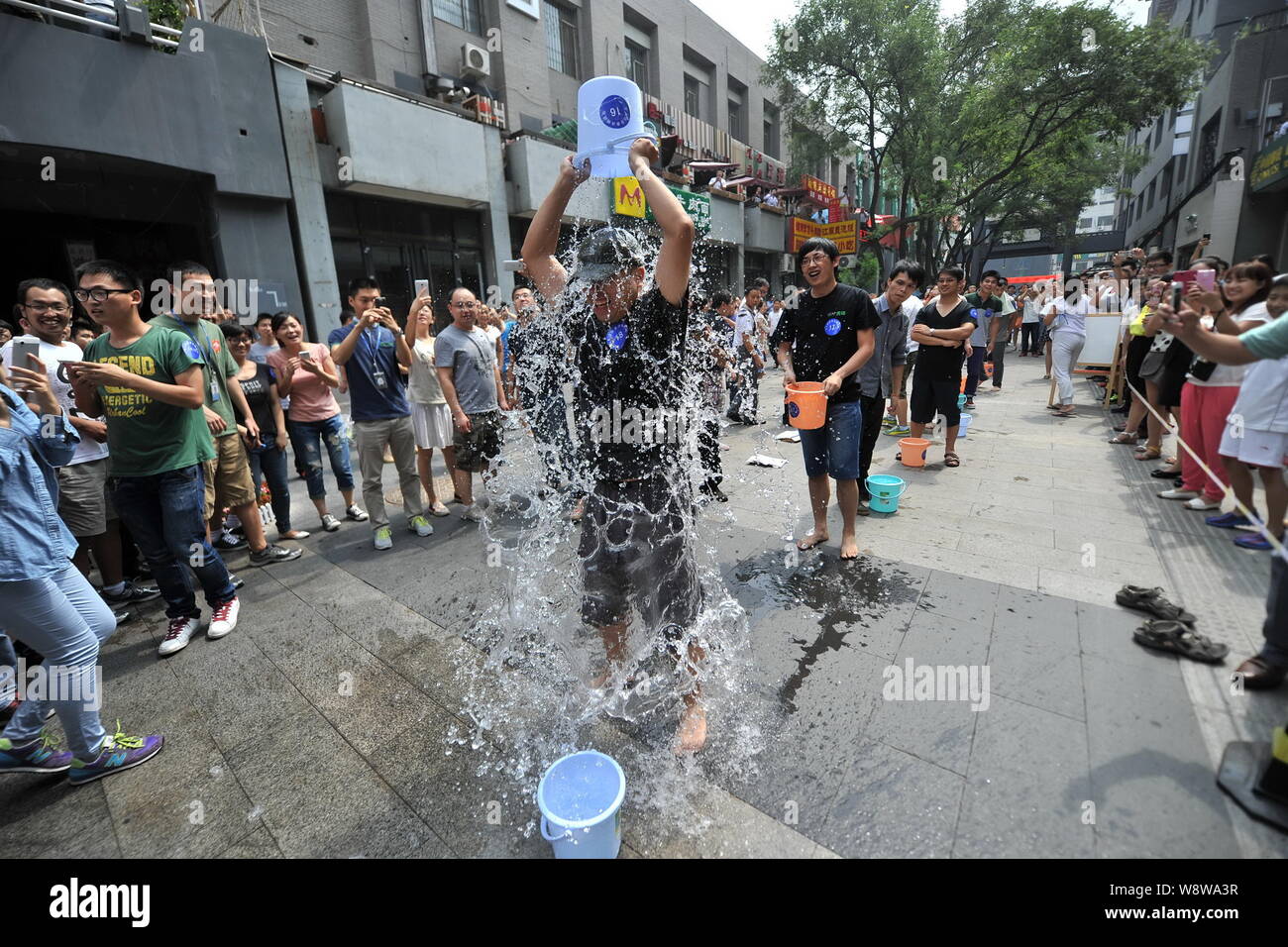 Young people line up along a street to brave the Ice Bucket Challenge ...