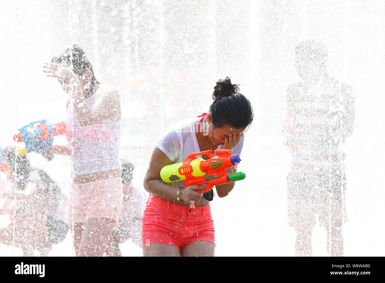 People play with water in a fountain to cool down on a scorching day in ...