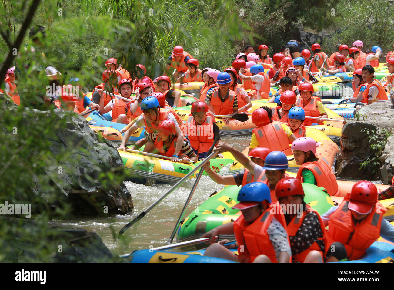 Crowds of tourists sit in their inflatable rafts as they enjoy rafting ...