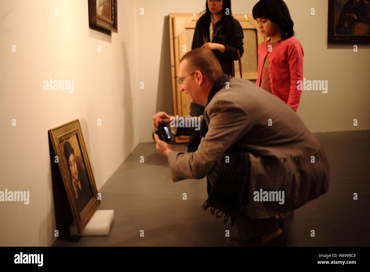 A foreign visitor takes photos of the painting, Woman in Black Hat, by ...