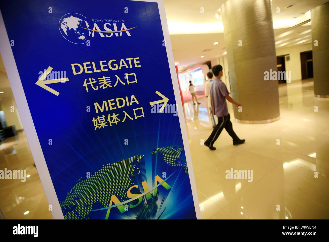 Staff members walk past a direction board ahead of the Boao Forum for ...