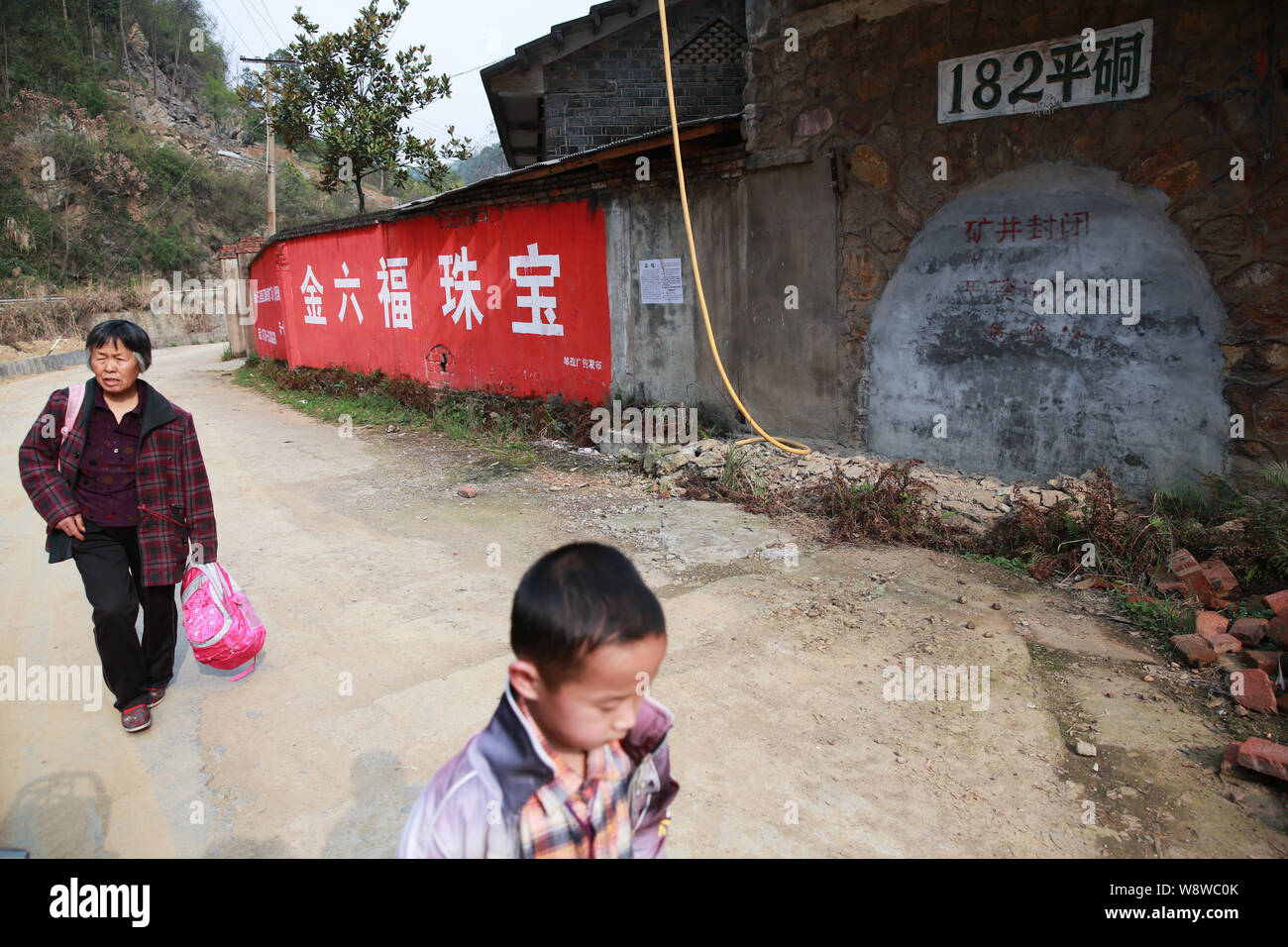 Chinese villagers walk past the sealed-off shaft of the realgar mine in ...