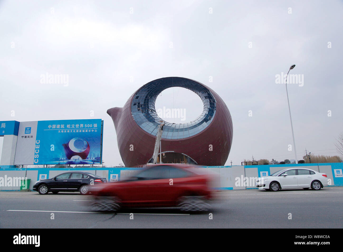 Cars pass by a teapot-shaped building, part of the Wuxi Wanda Cultural ...