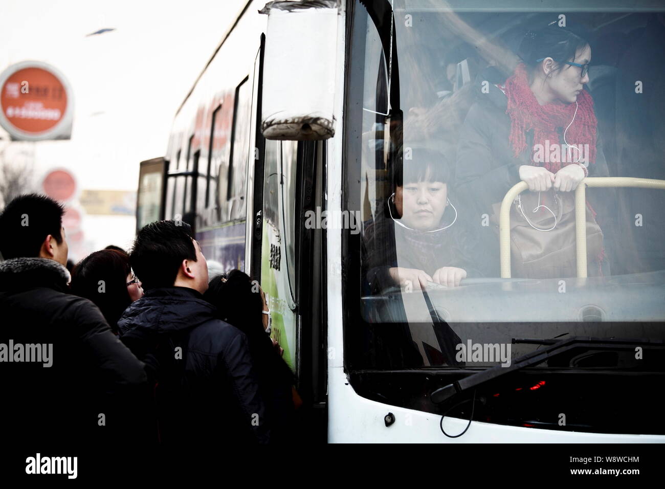 --FILE--Chinese passengers queue up to board an overcrowded bus to go ...