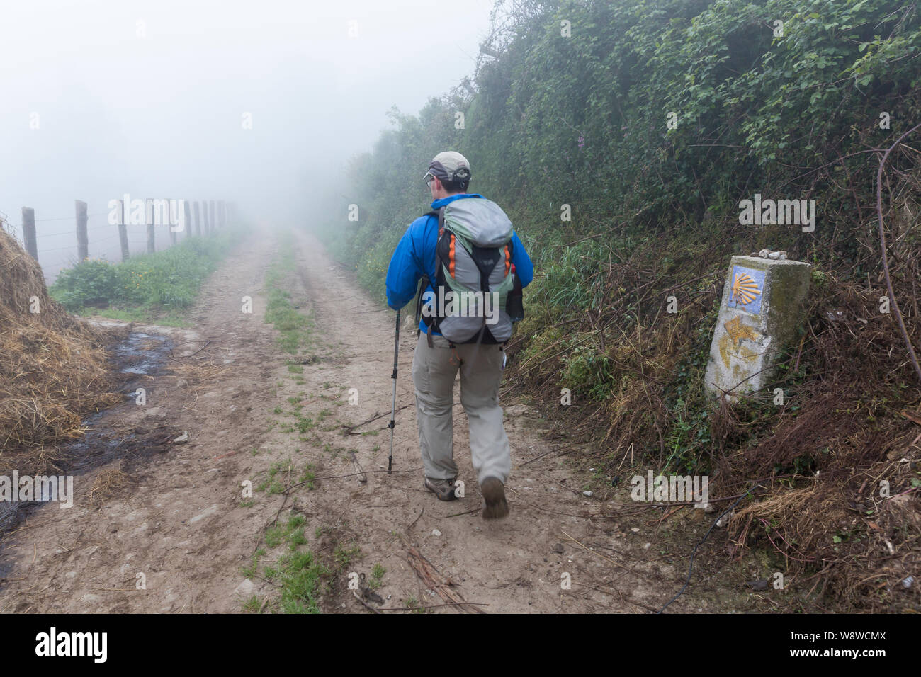 A lone pilgrim passes a marker on a farm road near the village of La ...